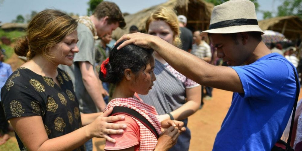 missionaries praying for someone lay apostolate - Crossroads Initiative